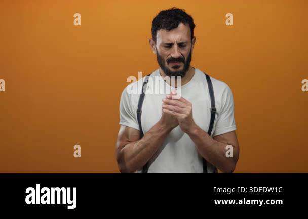 Hispanic man with beard stands against vibrant orange background ...