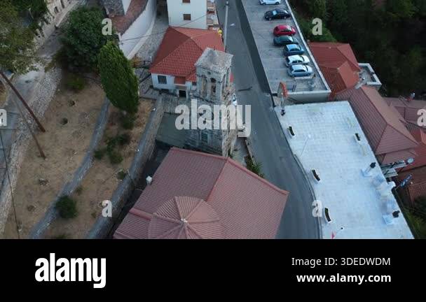 An old stone bell tower with a clock stands near the village square and ...