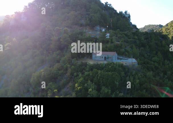A small traditional stone Orthodox church stands beside a mountain ...