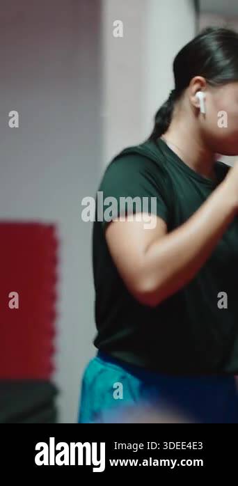 Athletic young woman with headphones practicing punches and speed ...