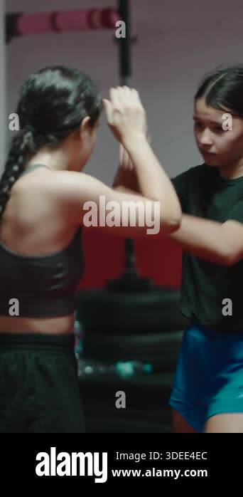 Two athletic women training together focused on punches and kicks ...