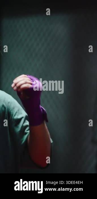 Concentrated young woman with hand wraps practicing her punches during ...