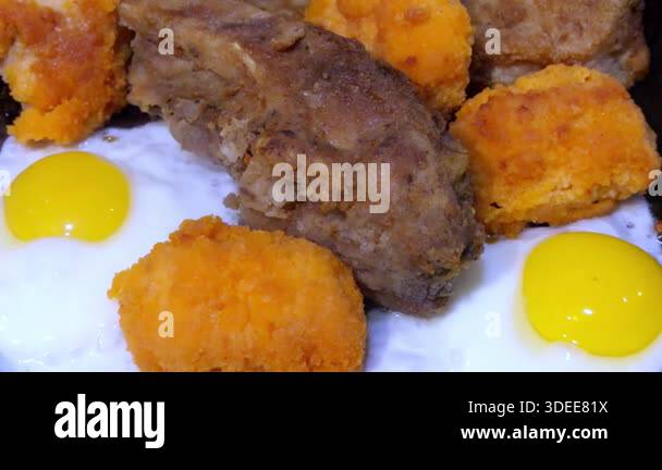 Breaded fish pieces and fried eggs in close up in the pan Stock Video ...