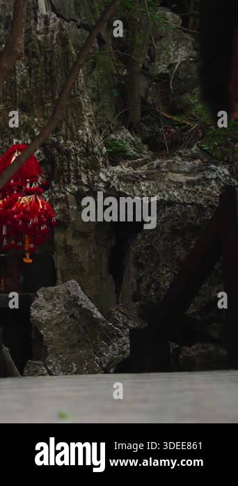 Young barefoot woman praying at a rocky buddhist altar with red ...
