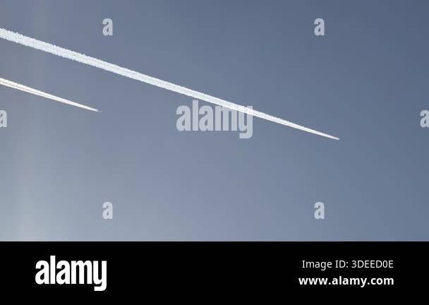 Two jet airplanes soaring at high altitude across a clear blue sky ...