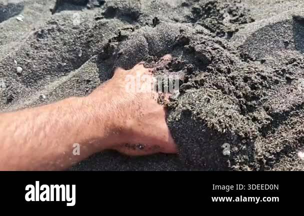 Close up of a mans hand slowly sinking and getting buried under the ...