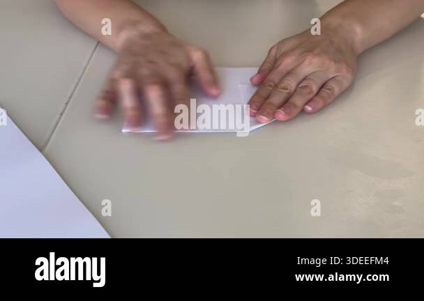 hands folding paper airplane on table white sheet transformed into dart ...