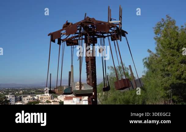 Abstract rusty metal sculpture with hanging elements outdoors against ...