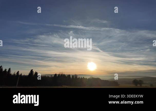 A breathtaking sunrise unfolds over a tranquil landscape, with clouds ...