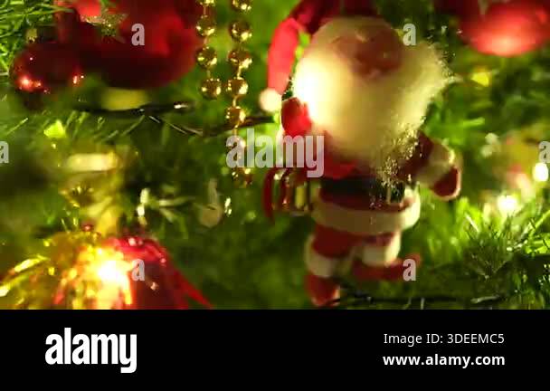 Small santa claus figure ornament hanging on a lush green christmas ...