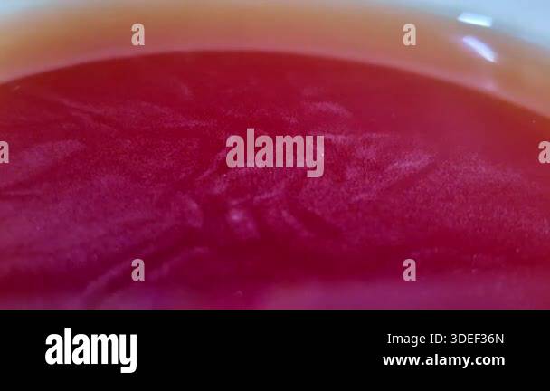 An extreme close-up shot focuses on the surface of a black coffee in a ...