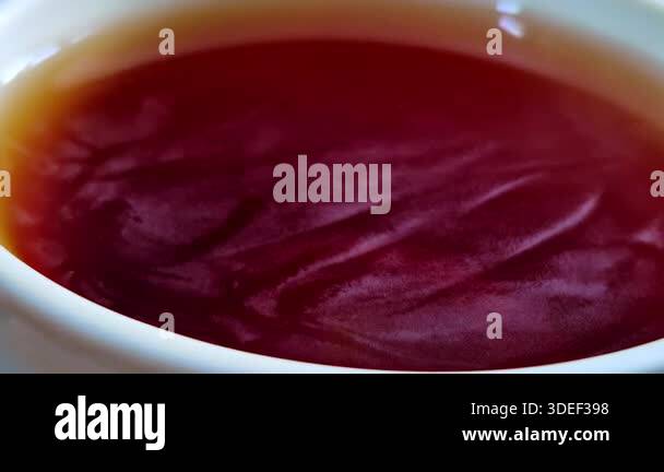 Zooming in closer on the vibrant reddish-amber black coffee ...