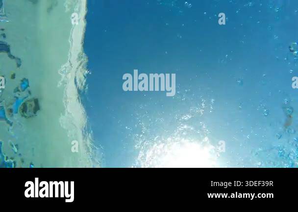 View from bottom of pool to unrecognizable man swimming on back with ...