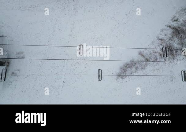 Aerial view of snow-covered landscape showcasing ski lift cables ...