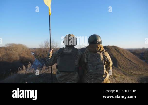 Military couple of ukrainian army sitting on lawn with Ukraine flag at ...