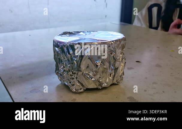 A close view shows a compact cylindrical object fully wrapped in ...