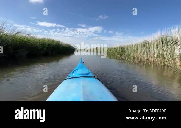 Canoeing through a canal at the farmland of Friesland the Netherlands ...