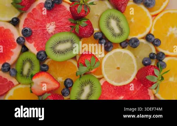 Background of fresh fruit slices with berries. Rotating shot of ...