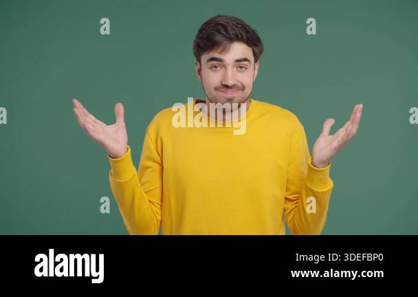 Man in yellow clothes lifts shoulders and hands in I dont know gesture ...
