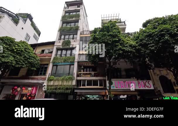 Tall building surrounded by trees and shops Stock Video Footage - Alamy