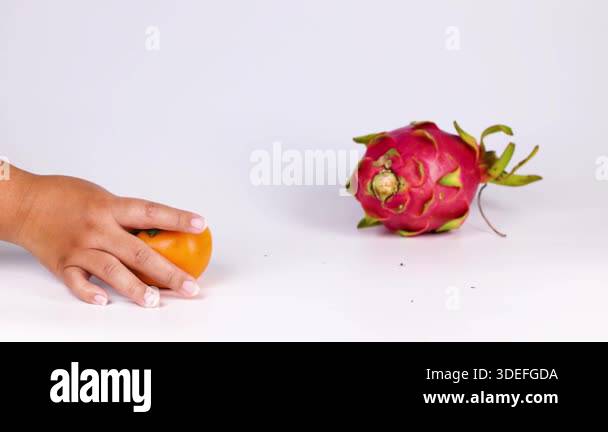 Hands reaching for dragon fruit and persimmon Stock Video Footage - Alamy