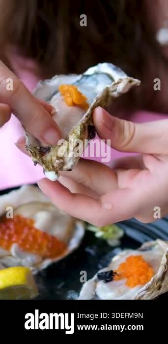 Hands opening fresh oysters with lemon slice on small plate. High ...