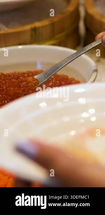scooping up red caviar with a spoon at a seafood buffet. High quality ...