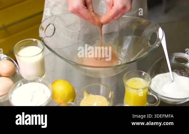 Mixing eggs with milk whisking dough in a glass bowl. A woman stirs ...