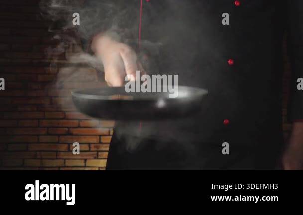 A chef stands in the kitchen, preparing food. Smoke rises from the ...