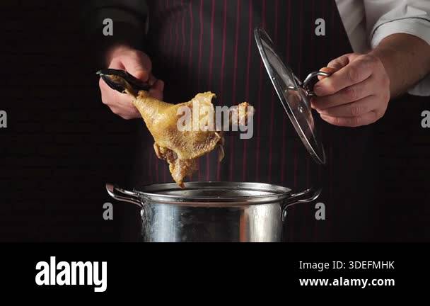 A chef holds and puts a chicken leg with tongs above a pot showing the ...