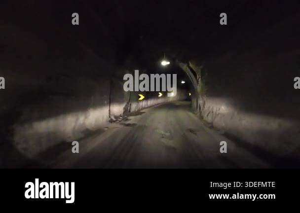 Point of view shot driving inside a dark rock tunnel and exiting to a ...