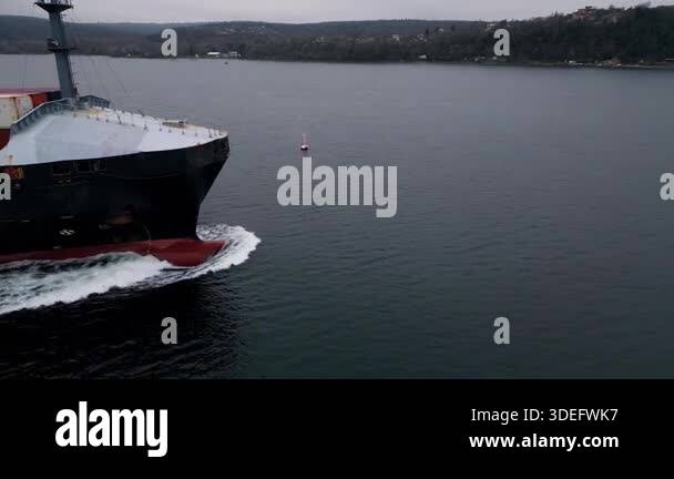 Close aerial view of container ship bow moving through calm water ...