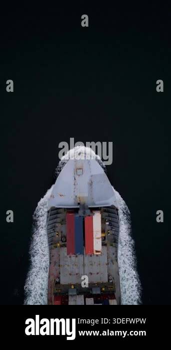 Top-down aerial view of container ship cutting through dark water ...