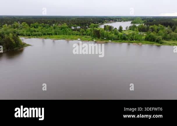Aerial drone pulls back over wide lake with small islands, parked vans ...
