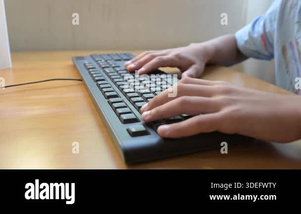Close-up of hands typing on a computer keyboard at a desk. Everyday ...