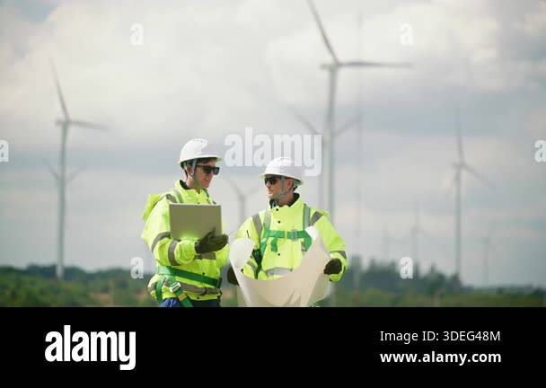 Engineers wearing safety helmets working on site in wind turbine farm ...