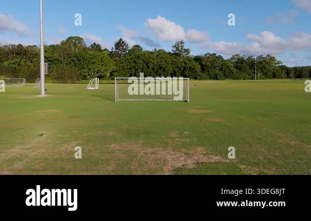 Drone footage captures an empty soccer field with goals under clear ...