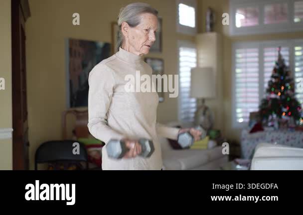 Elderly woman performs her morning exercise routine with weights in her ...