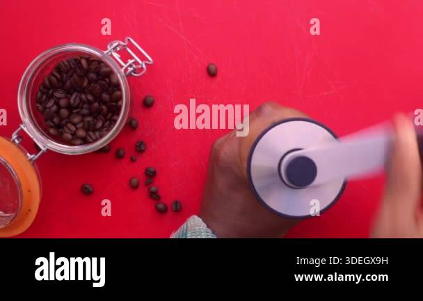 Top view of person's hands grinding roasted coffee beans on red ...