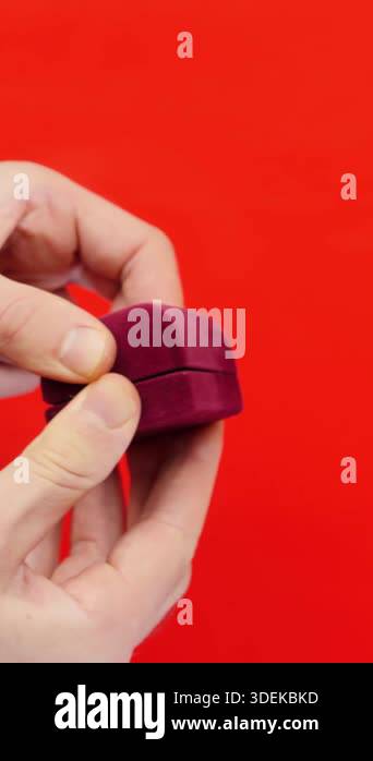 Man is holding wedding ring in box for proposal on red background. Hand ...