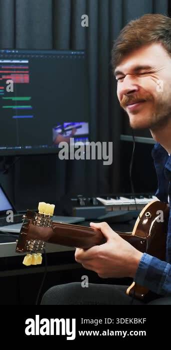 Guitarist in blue shirt and headphones playing on electric guitar at ...