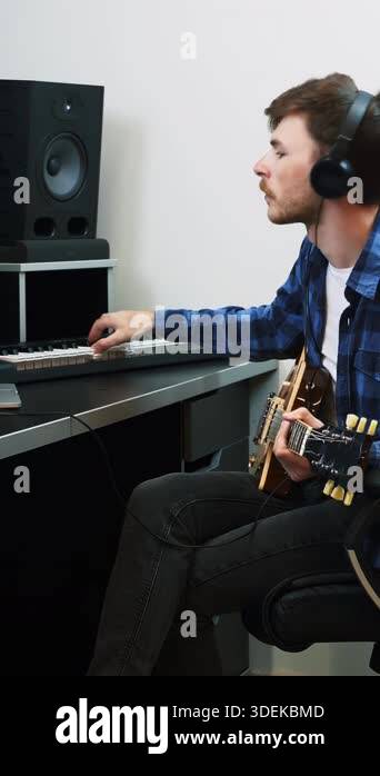Man playing on midi piano keyboard and electric guitar and recording ...