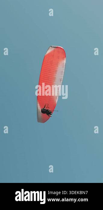 Flying red parachute against blue cleat sky. Tourist person glides with ...