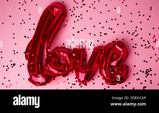 Red shiny love letters balloon on pink with scattered heart shaped ...