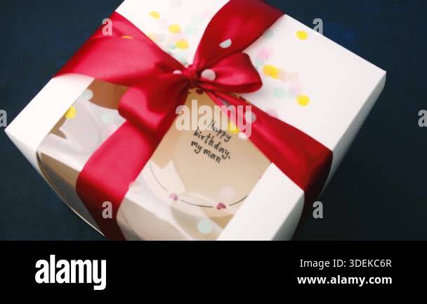 White gift box with red ribbon, confetti and birthday message tag ...