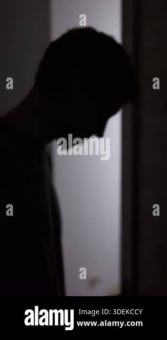 Man standing in doorway under emotional pressure, silhouette with hands ...