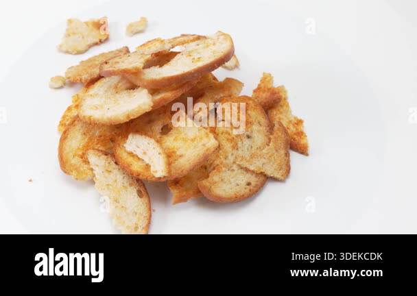 A small pile of baked bread chips rotates gently on a white surface ...
