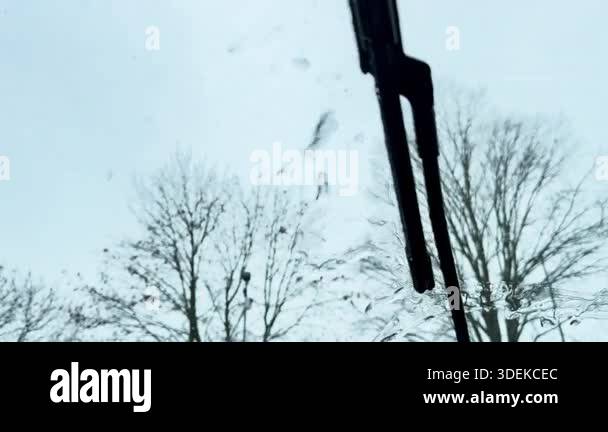 Car windshield wipers move across glass during winter weather, seen ...