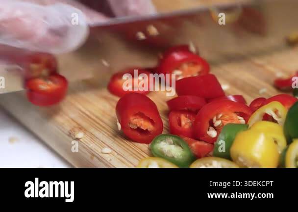 Colorful chili pepper slices scattered on a wooden board during food ...