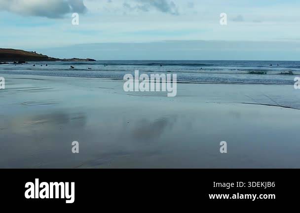 cloudy shoreline with surfers and choppy waves. High quality 4k footage ...